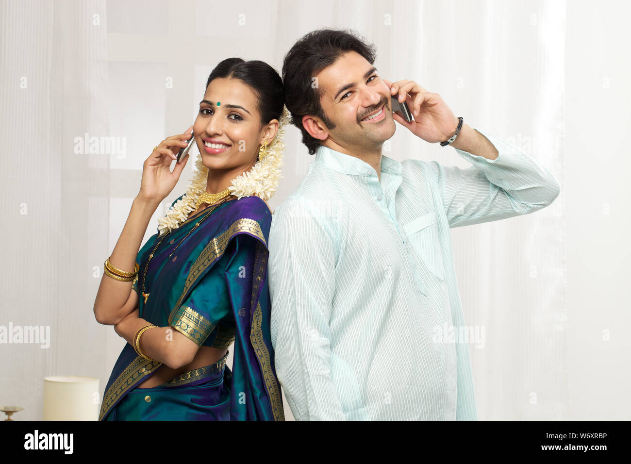 South Indian couple talking on mobile phones and smiling Stock Photo ...