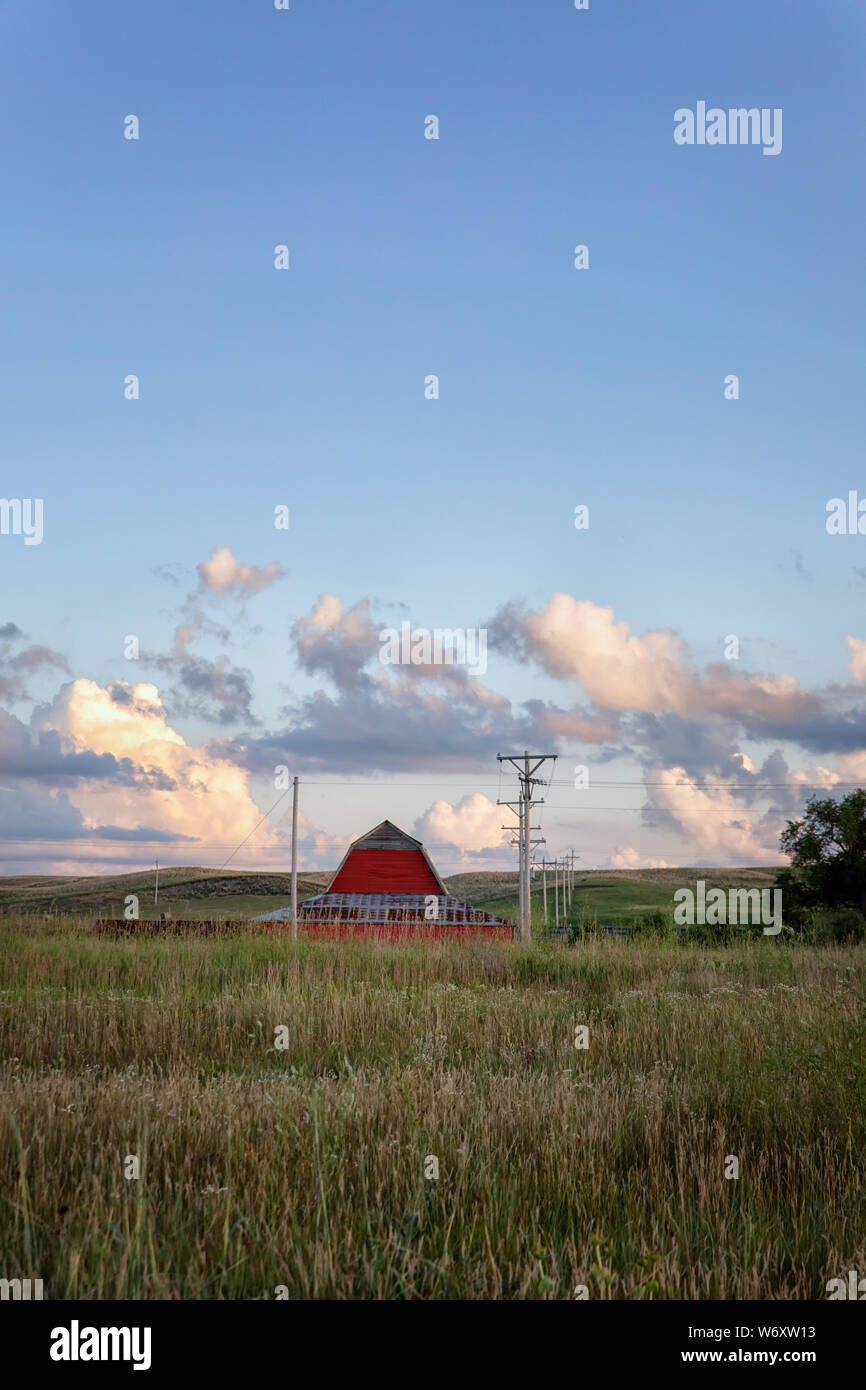Landscape photo of an abandoned red barn in a grassy field with clouds ...