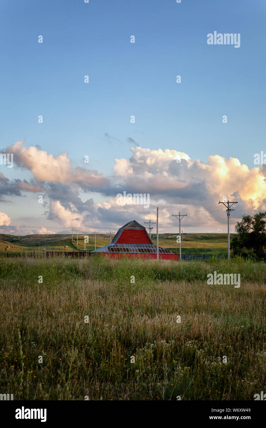 Landscape photo of an abandoned red barn in a grassy field with clouds ...