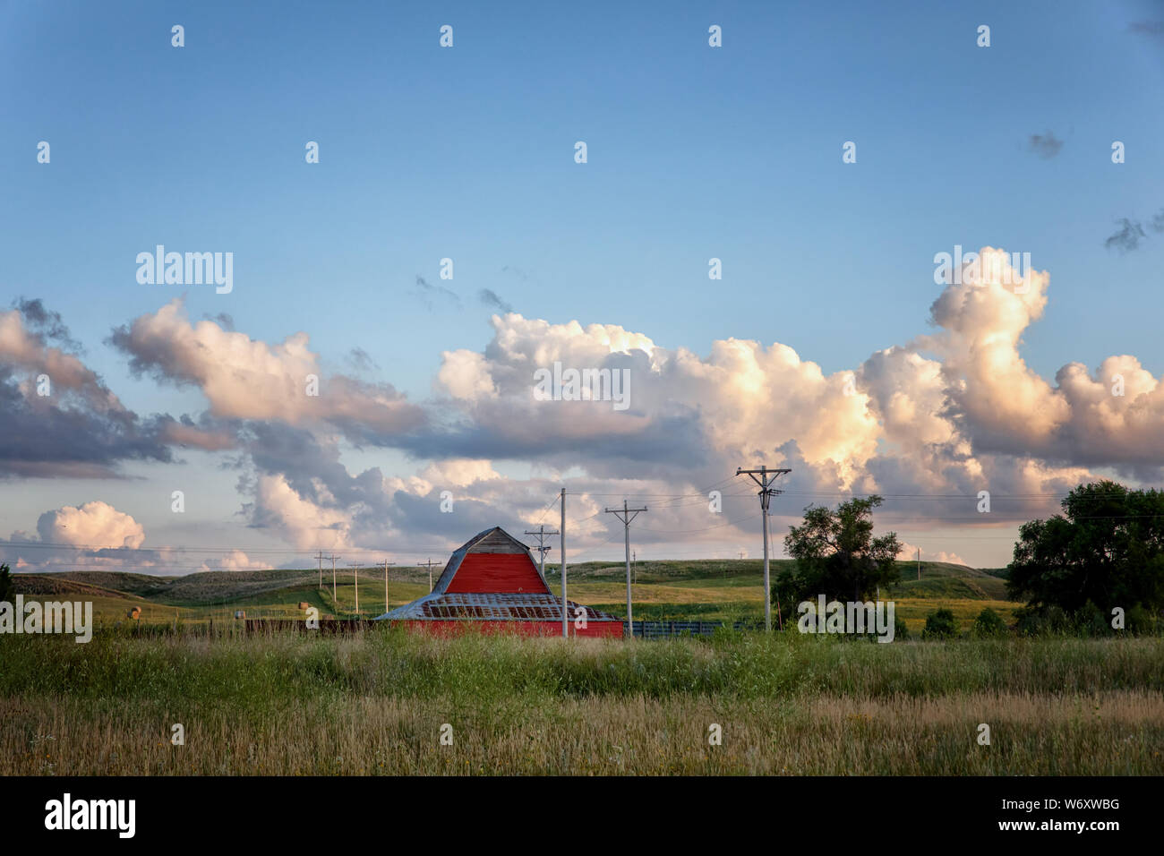 Landscape photo of an abandoned red barn in a grassy field with clouds ...