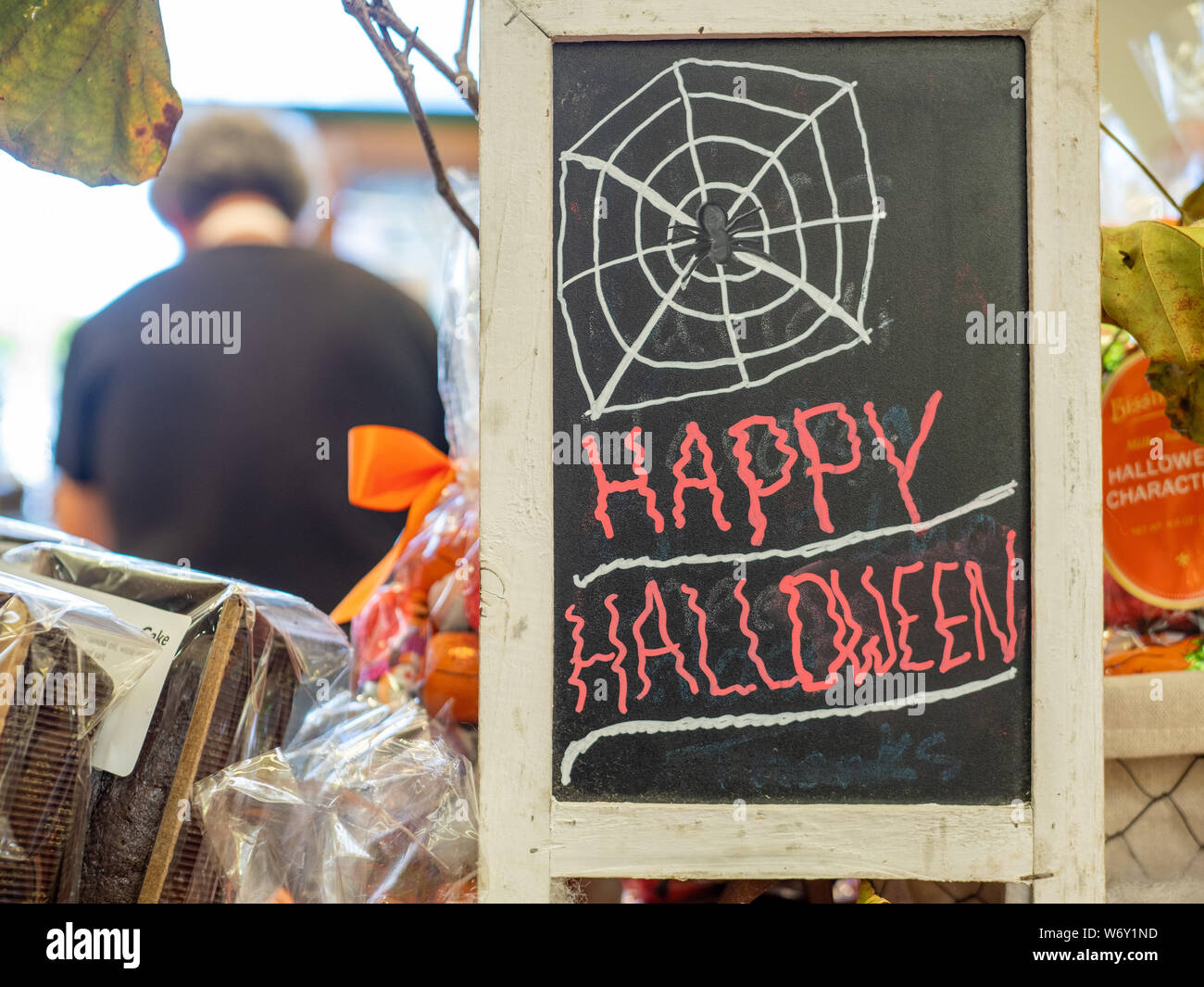 Happy Halloween spider web sign written in chalk on board at store with ...