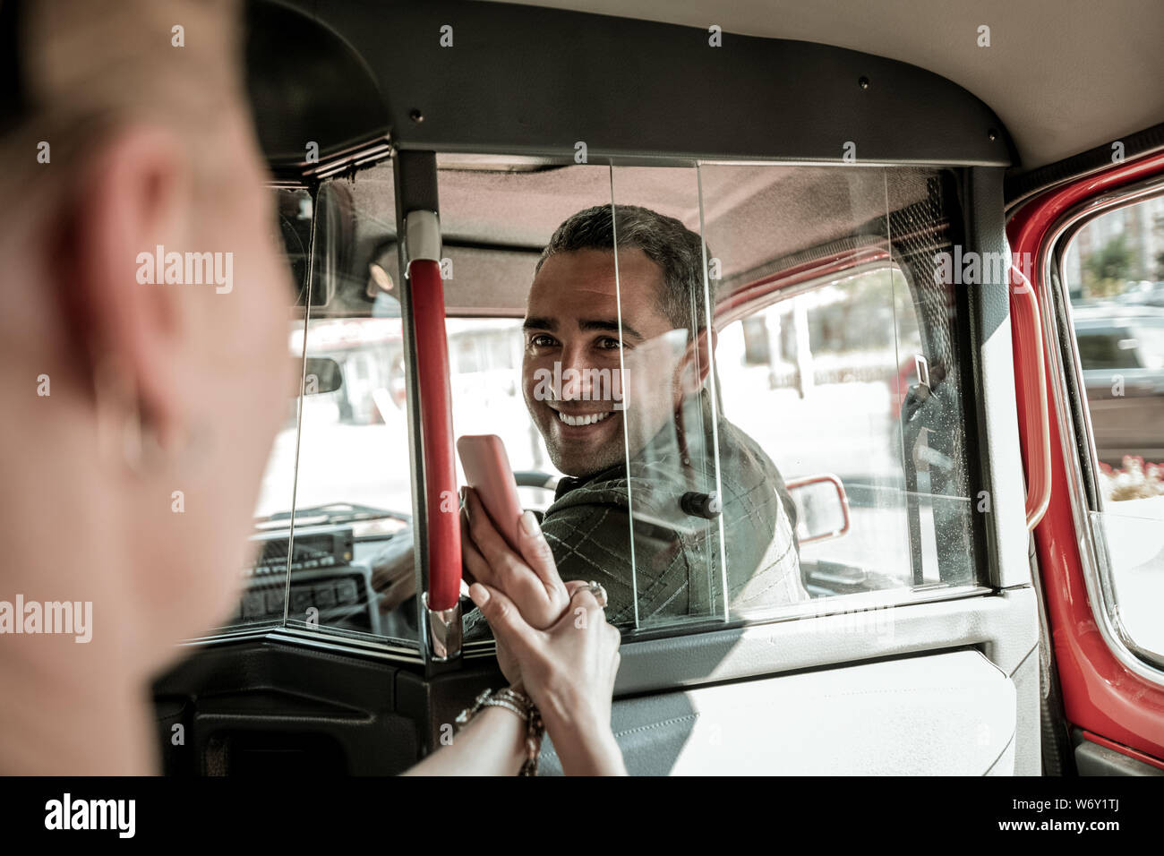 Car driver smiling to a woman on the backseat Stock Photo - Alamy