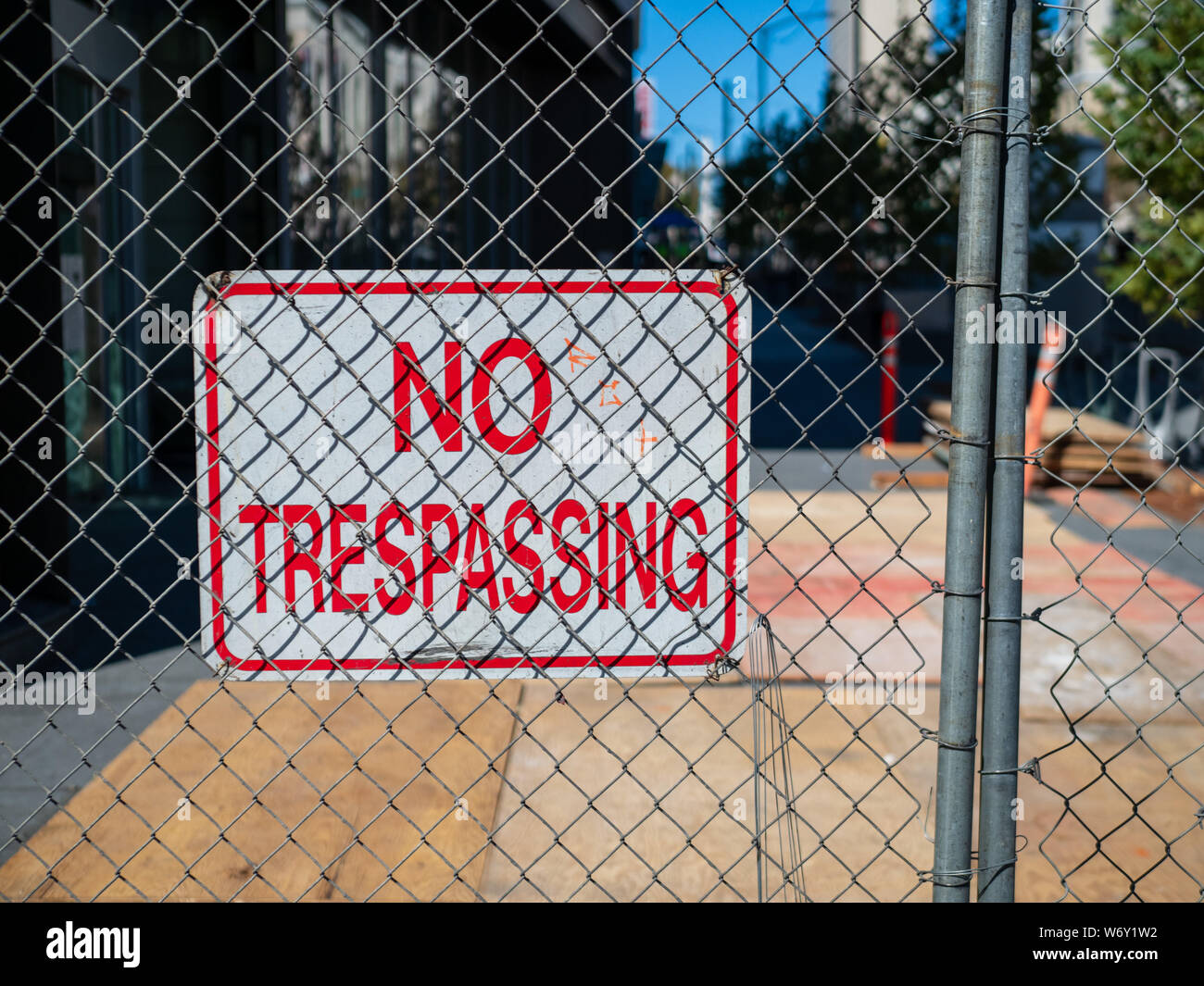 No trespassing sign behind fence wire in front of urban construction ...