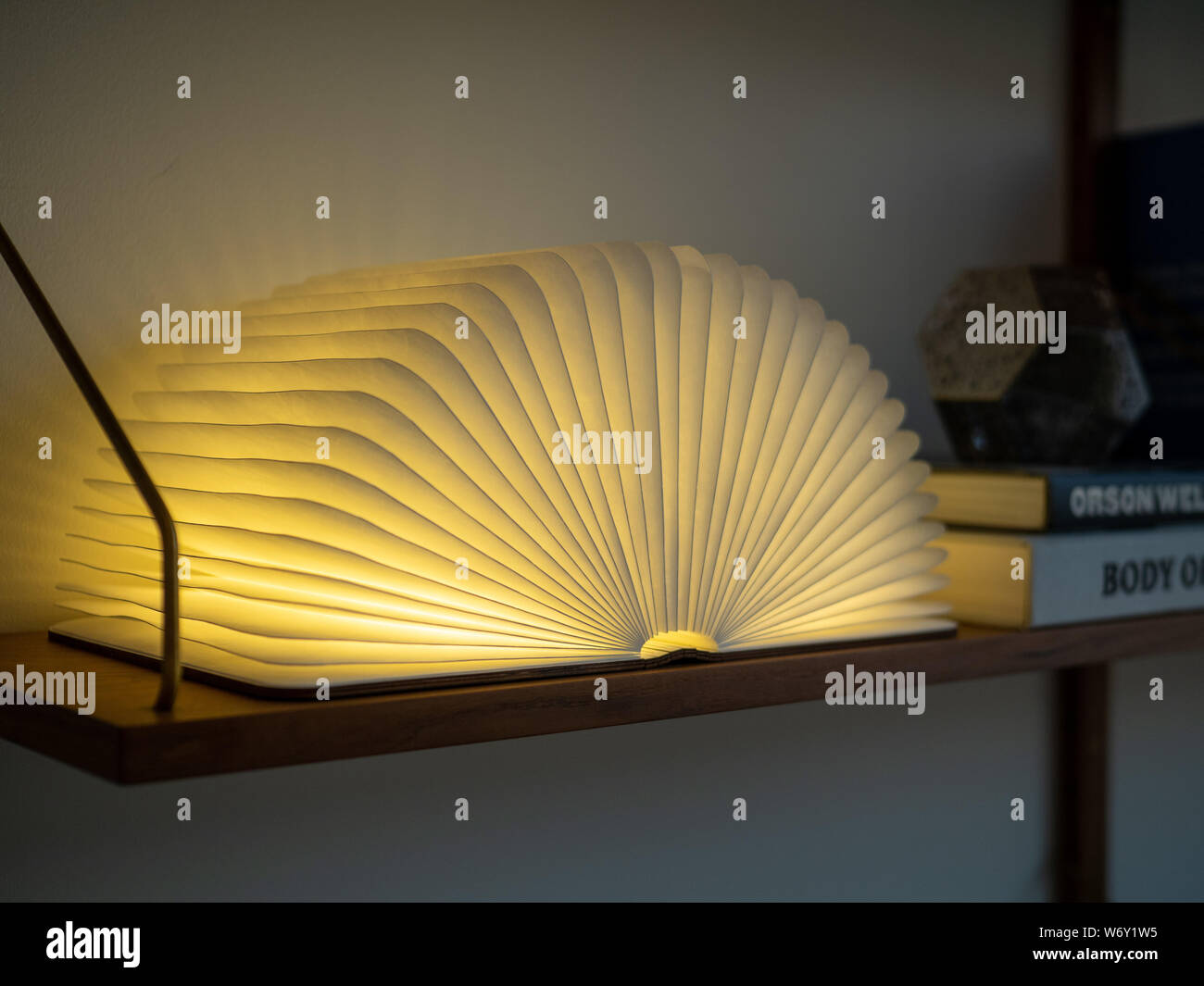 Lamp in the shape of an open book emits soft glow on shelf Stock Photo ...