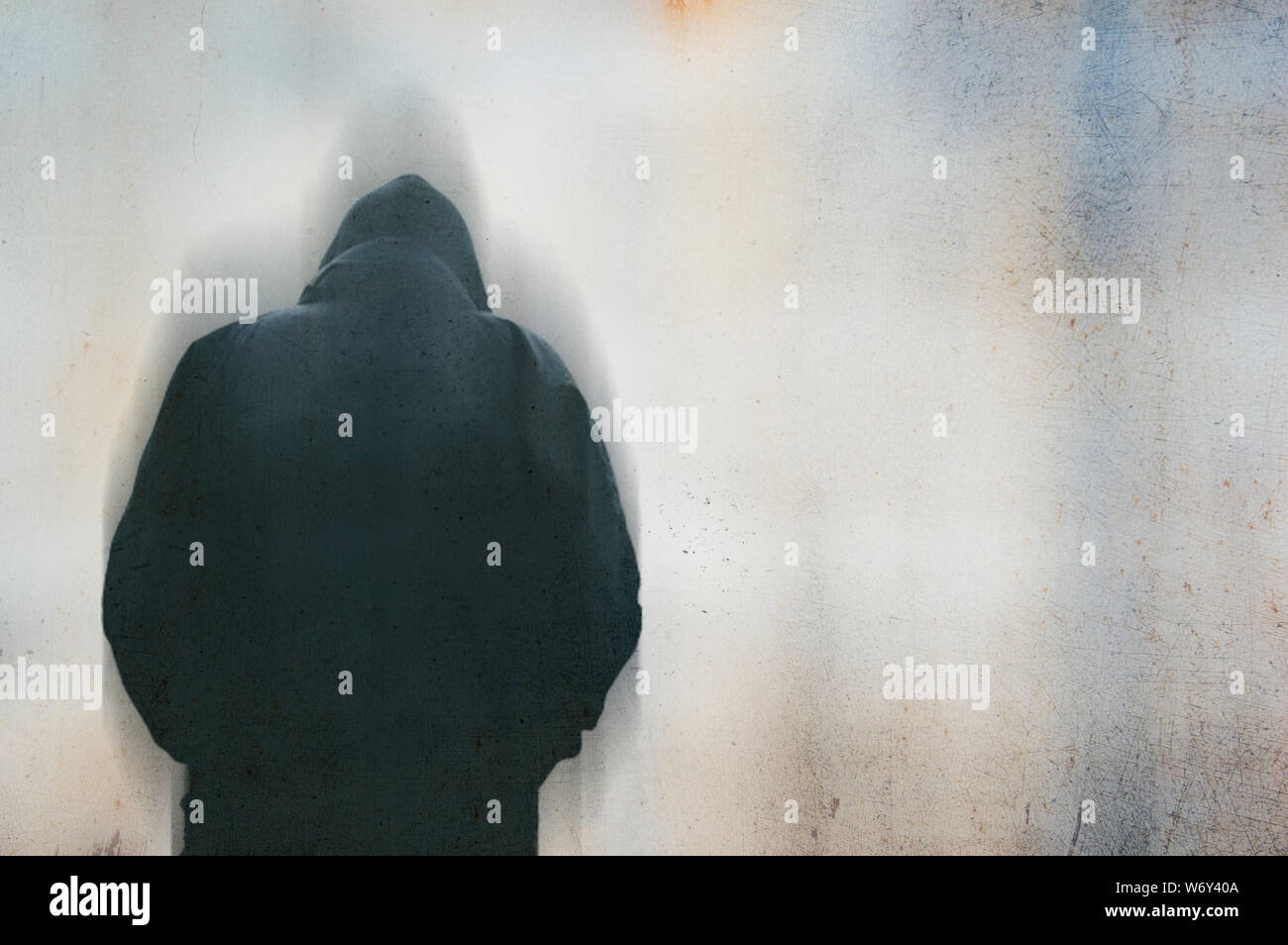 Back of a hooded man hunched and sad representing mental health issues ...