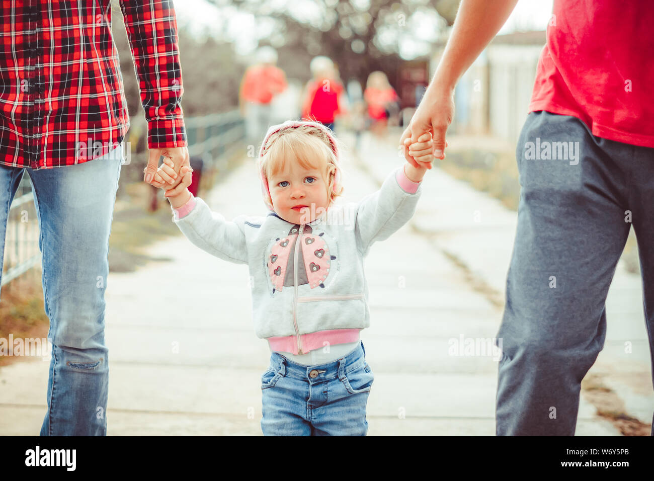 parents walk with child holding hands child laughs Stock Photo - Alamy