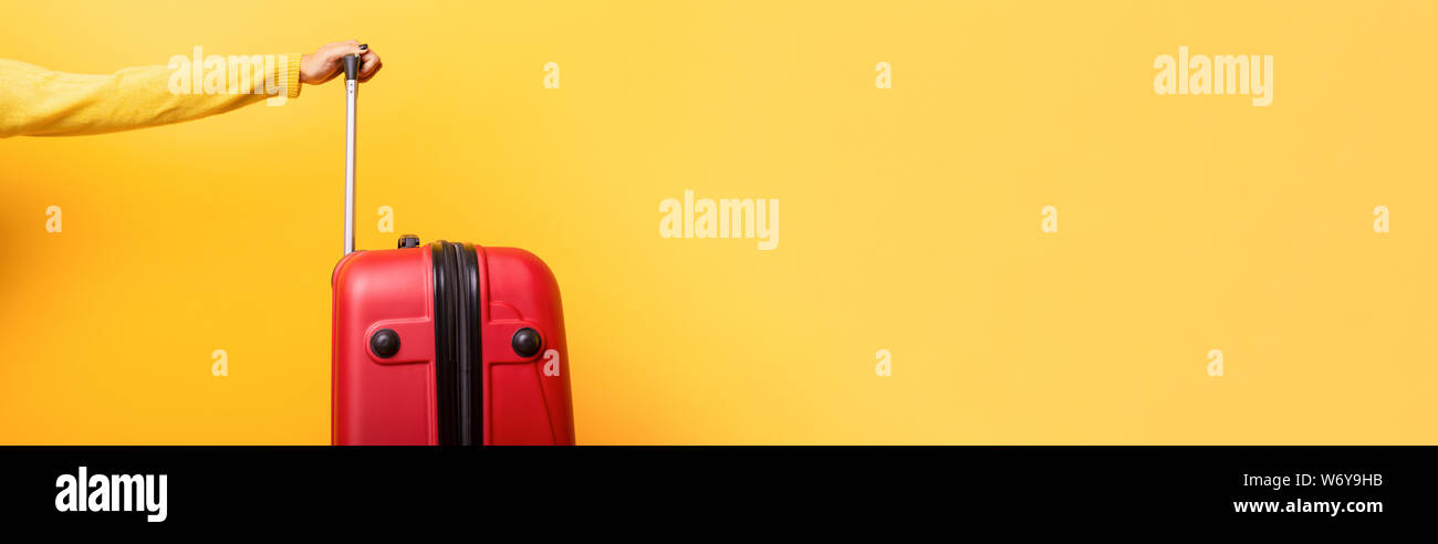 Travel red suitcase and hand over yellow background, panoramic mock up ...