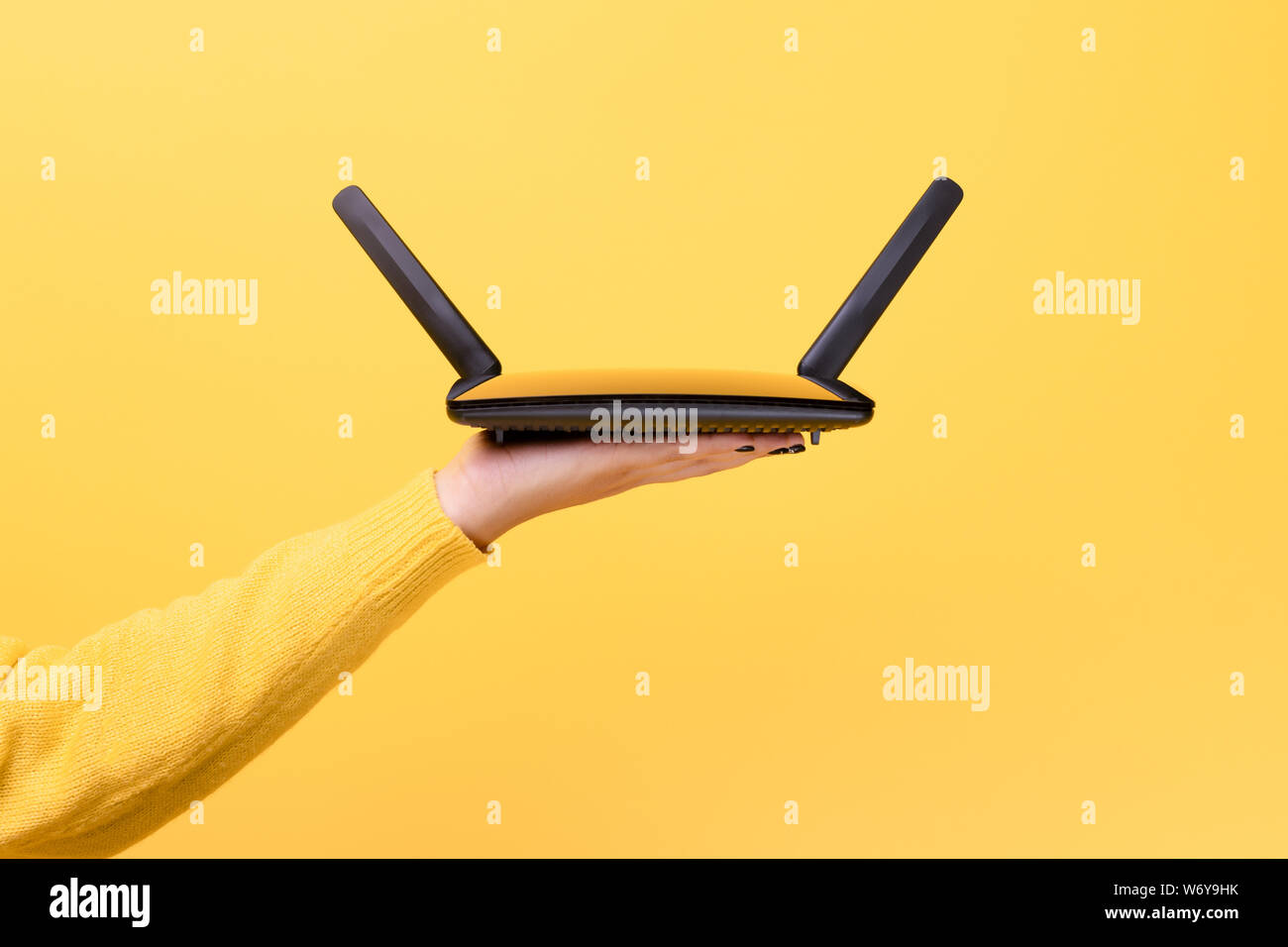 black wifi router on female hand over yellow background Stock Photo - Alamy