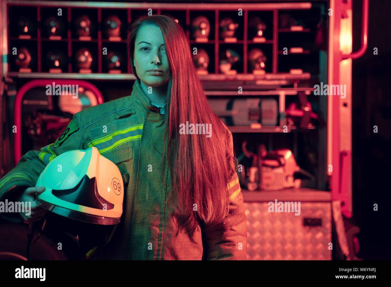 Photo of female firefighter with long hair with helmet in her hands at ...