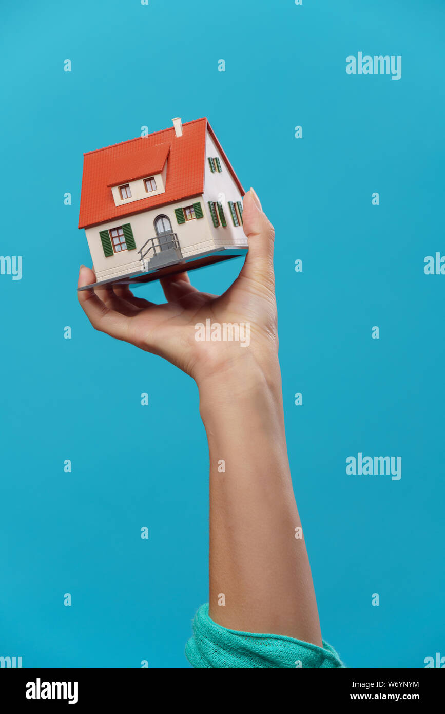 Image of hand with toy house on pure blue background Stock Photo - Alamy