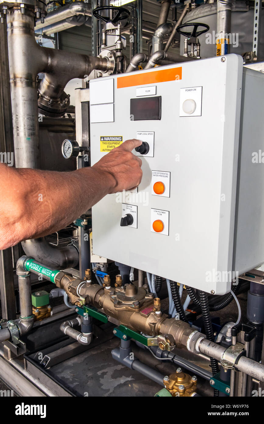 Industrial workers finger pushes button on control panel to maintain ...