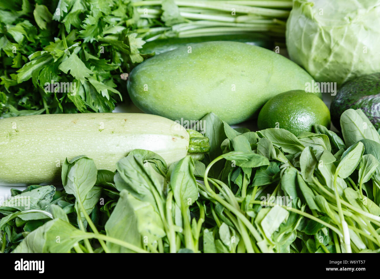 Fresh green vegetables variety on rustic white background from overhead, celery, avocado ...