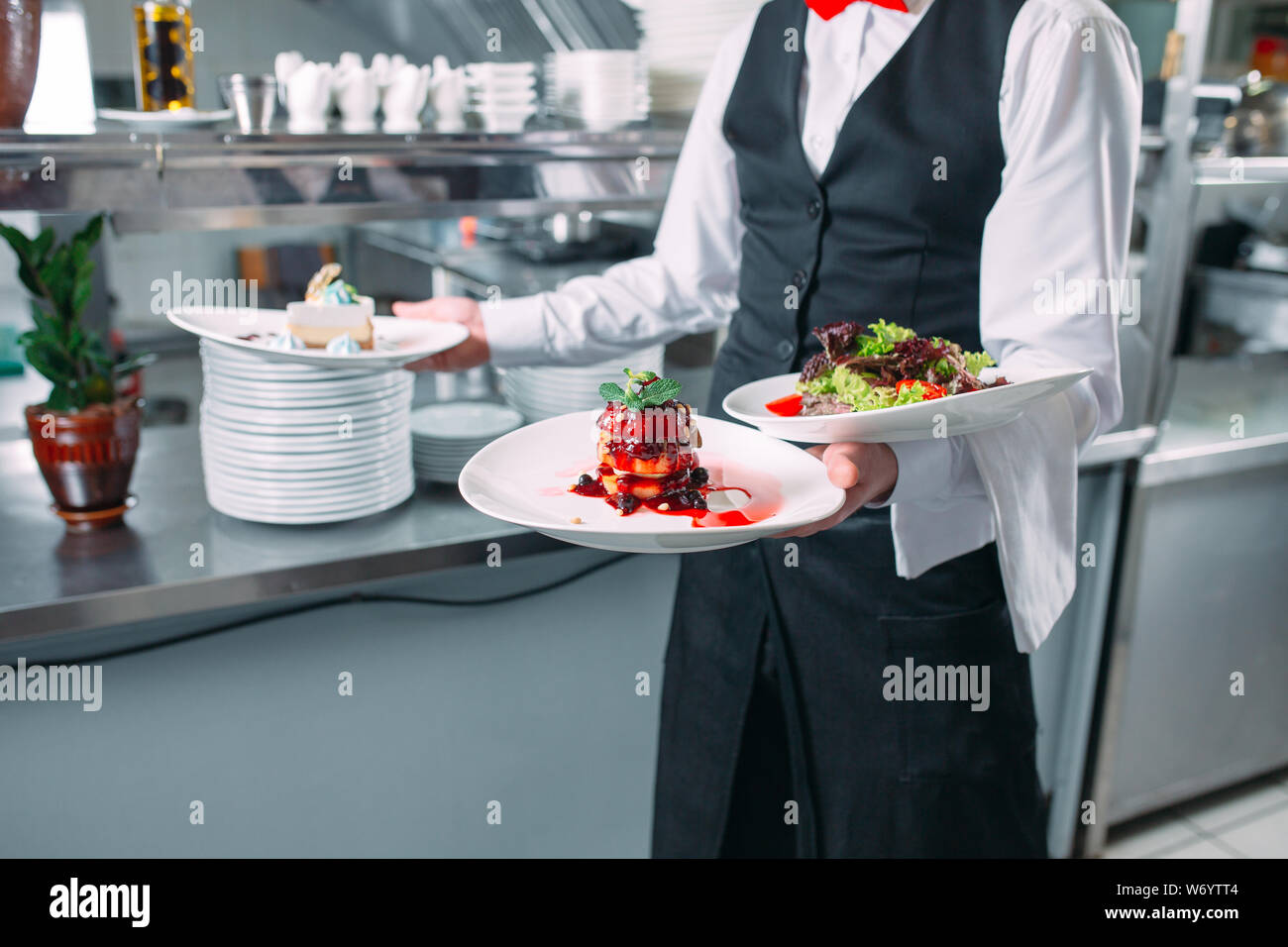 Waiter serving in motion on duty in restaurant. The waiter carries ...