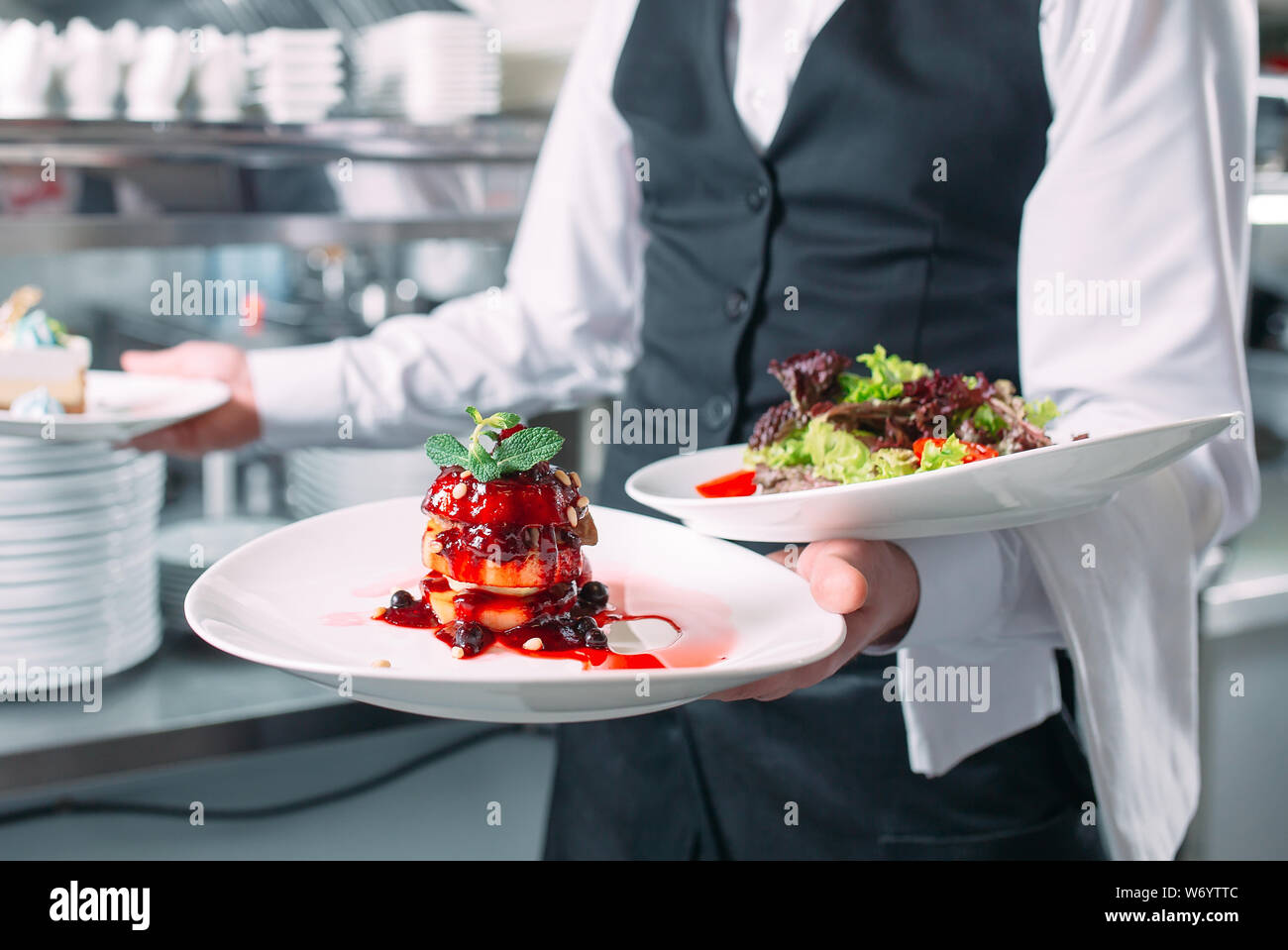 Waiter serving in motion on duty in restaurant. The waiter carries ...