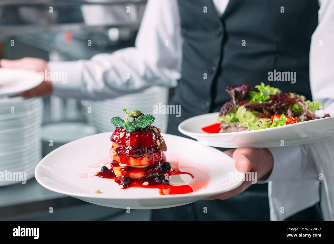 Waiter serving in motion on duty in restaurant. The waiter carries ...