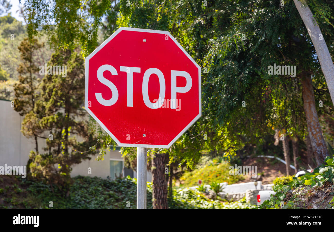 Stop road sign on an intersection. Blur trees and blue sky background ...