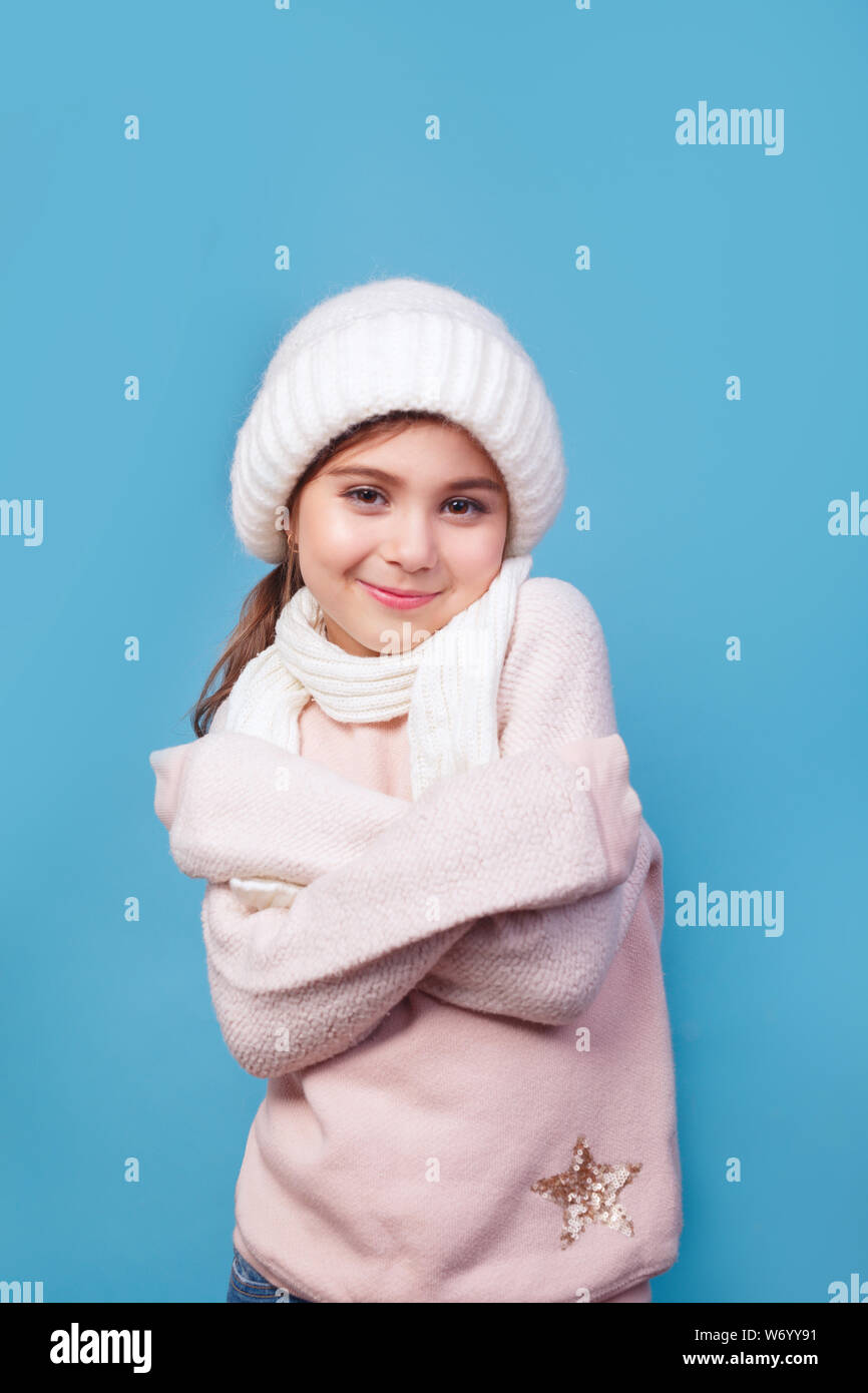 Cute little girl wearing white woolen cap and scarf on blue background ...
