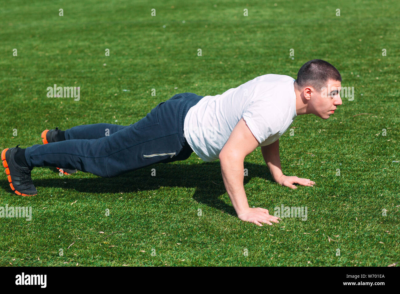 Fitness man plank workout training in park outdoors. Young guy makes ...