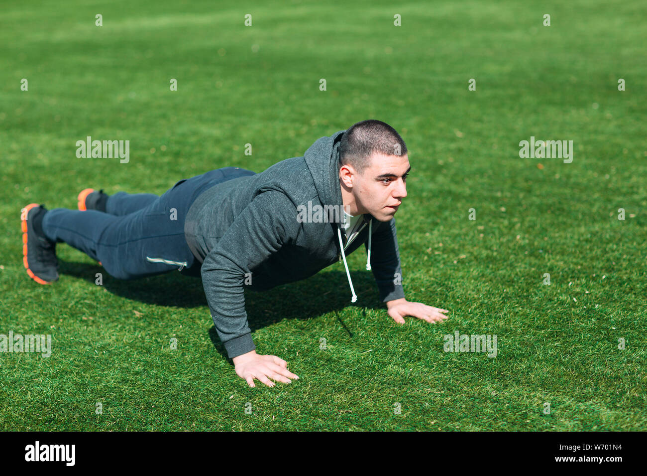 Fitness man plank workout training in park outdoors. Young guy makes ...