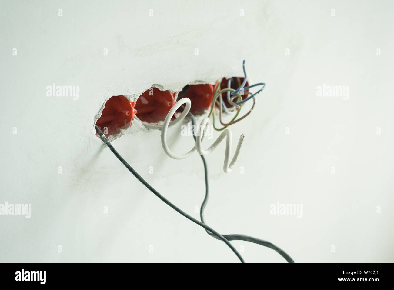 protruding wires from the outlet. Unfinished home repair on a white ...