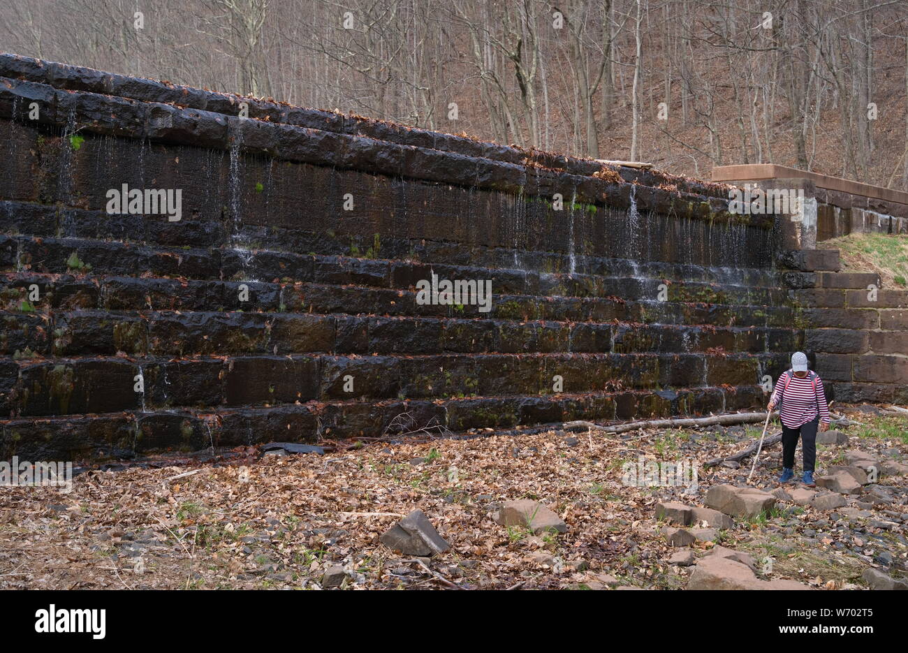 Water slowly seeping out from a reservoir wall at a hiking park as a ...