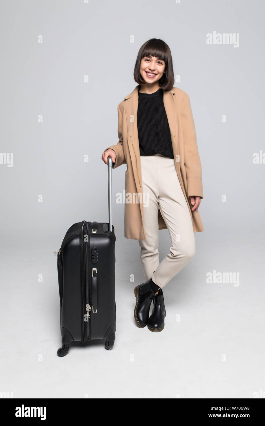 Beautiful young woman smiling and pulling luggage isolated on white ...
