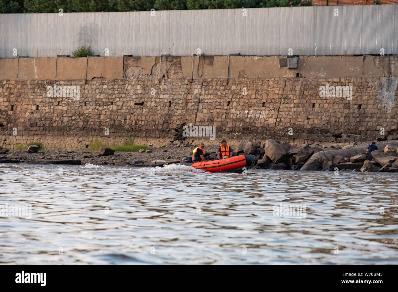 People in an inflatable boat floating on the Amur river along the shore ...