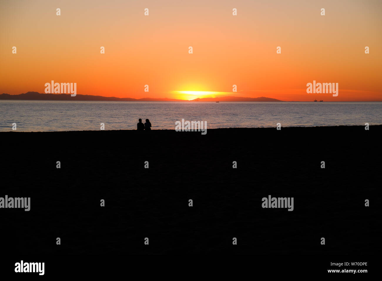 Watching sunset at the beach Stock Photo - Alamy