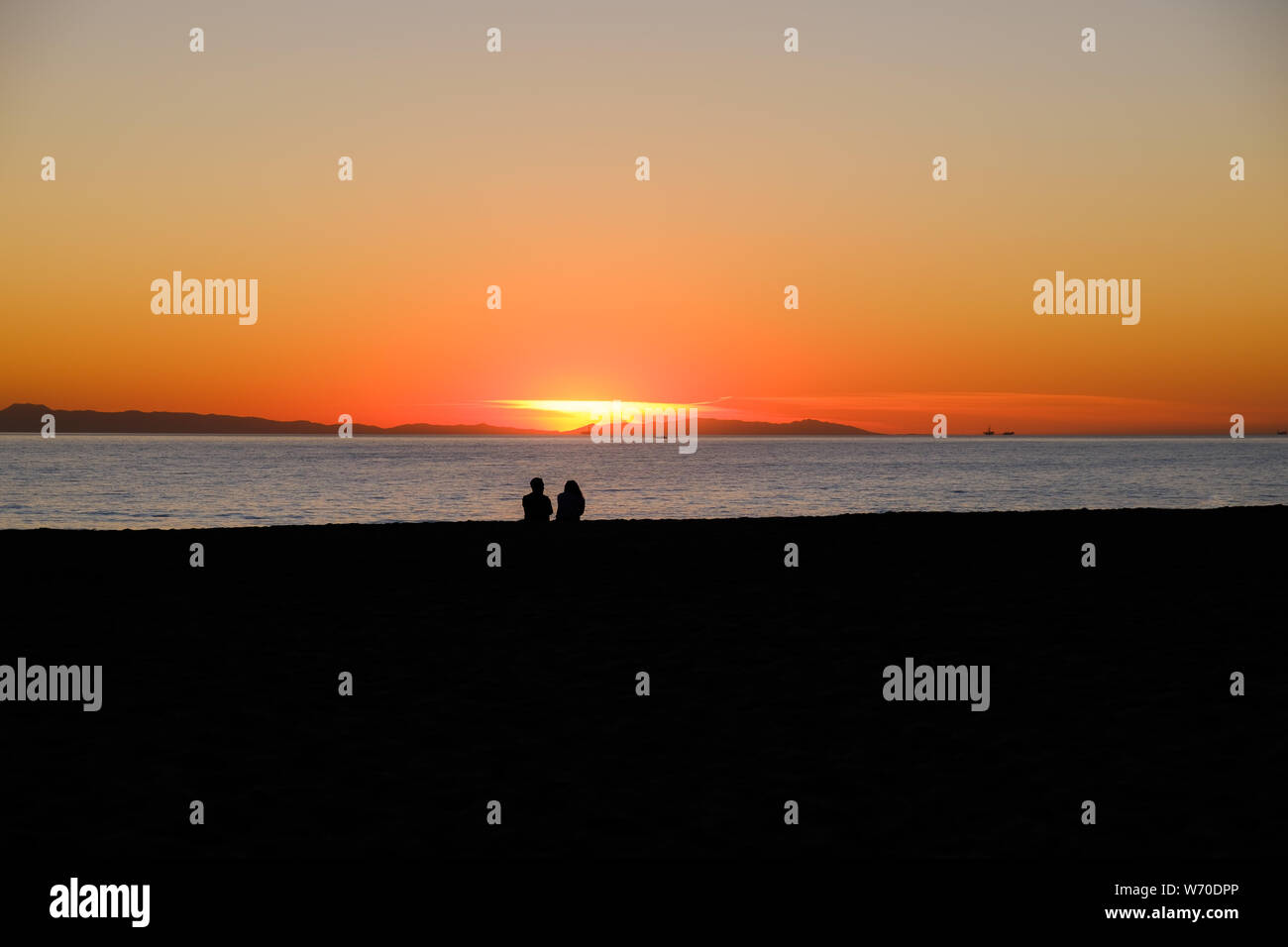 Watching sunset at the beach Stock Photo - Alamy