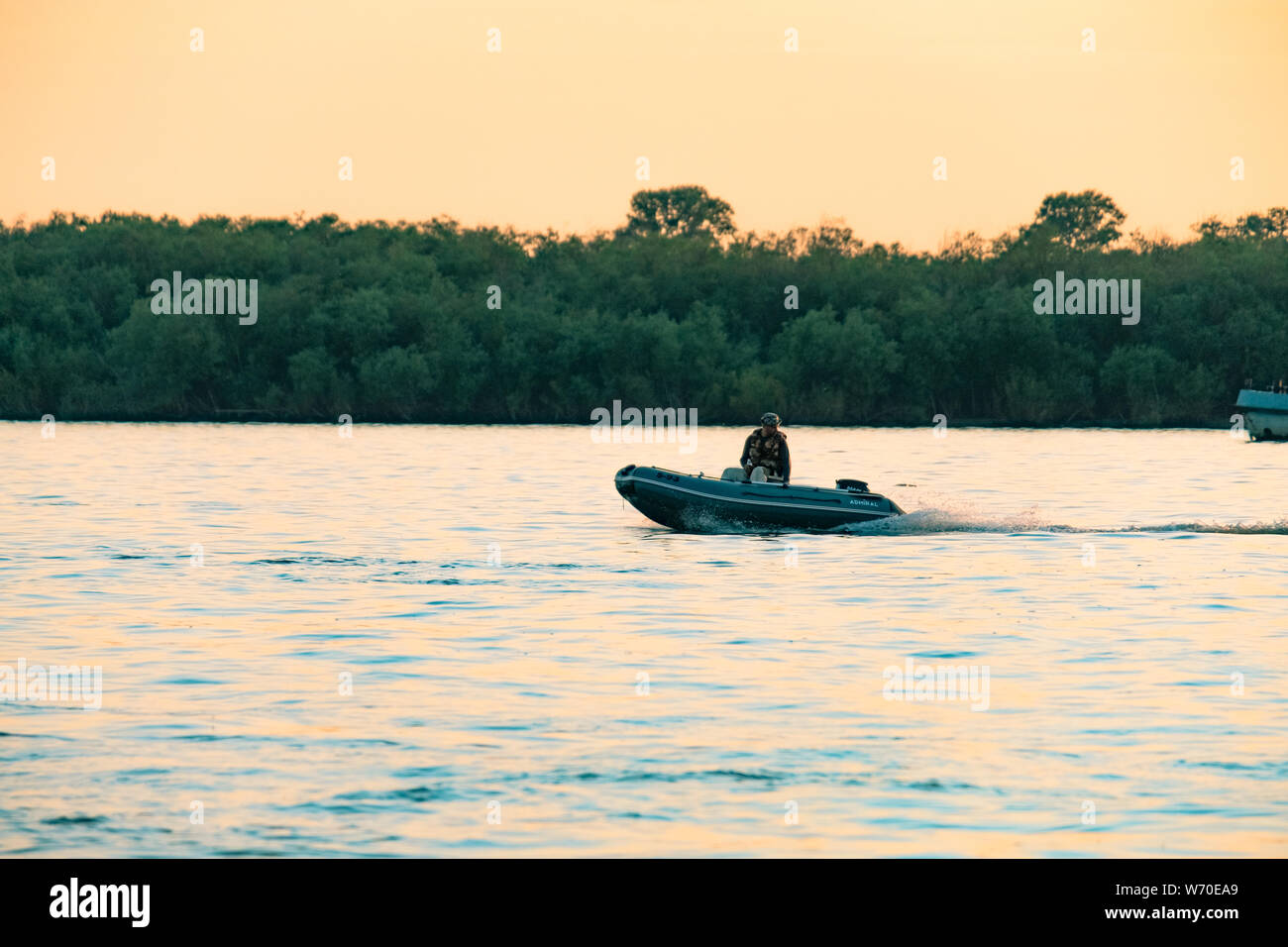 People in an inflatable boat floating on the Amur river along the shore ...