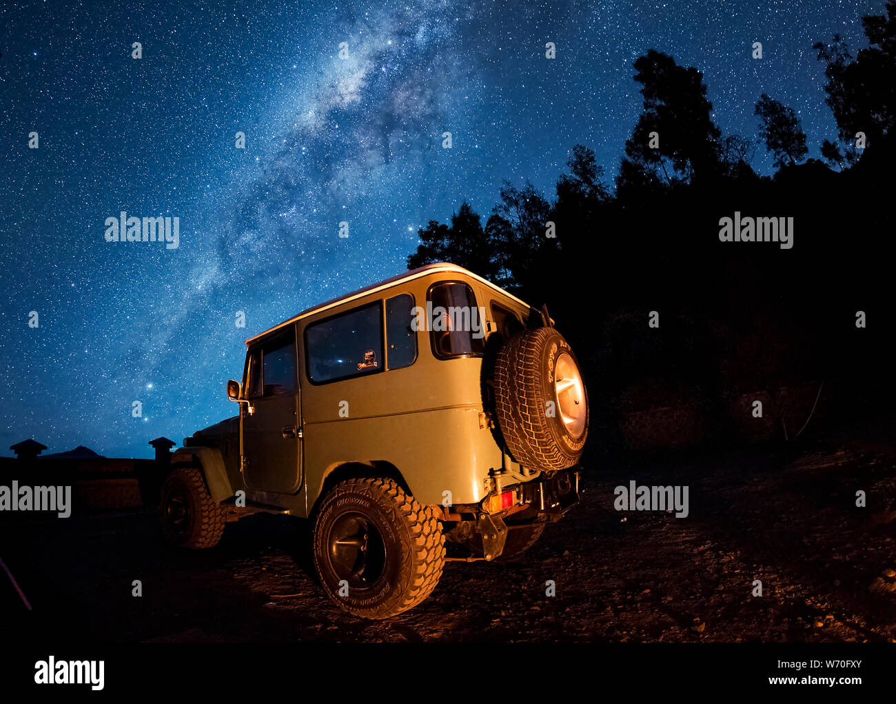 Tourist jeep parked at night and sky filled with shining milky way ...