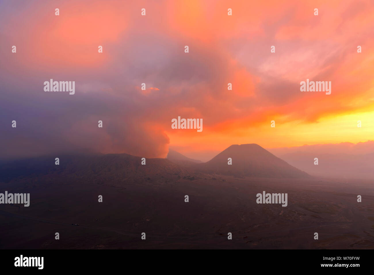 Orange sky glowing at sunset above erupting volcano Mount Bromo one of ...