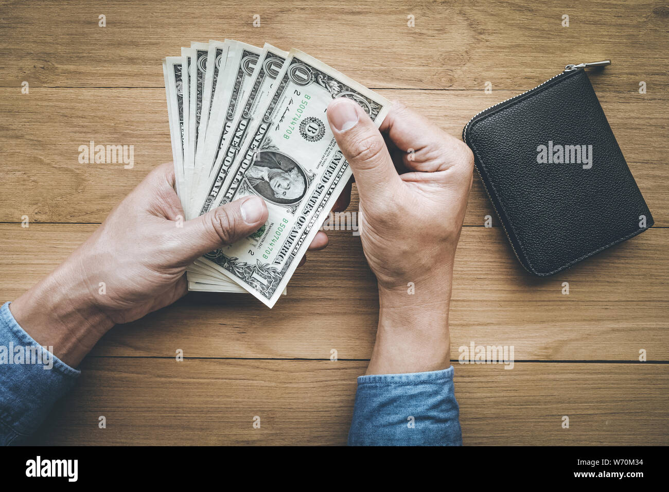 Male hand holing money dollar bill with wallet on wood table.business ...
