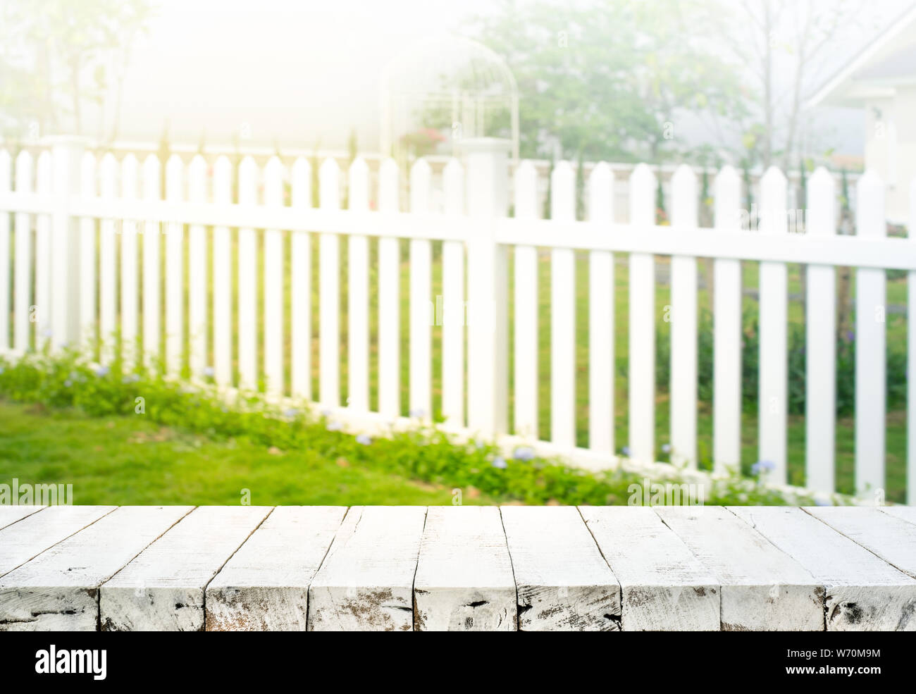 Wood table top on blur of white fence and garden background.For montage ...