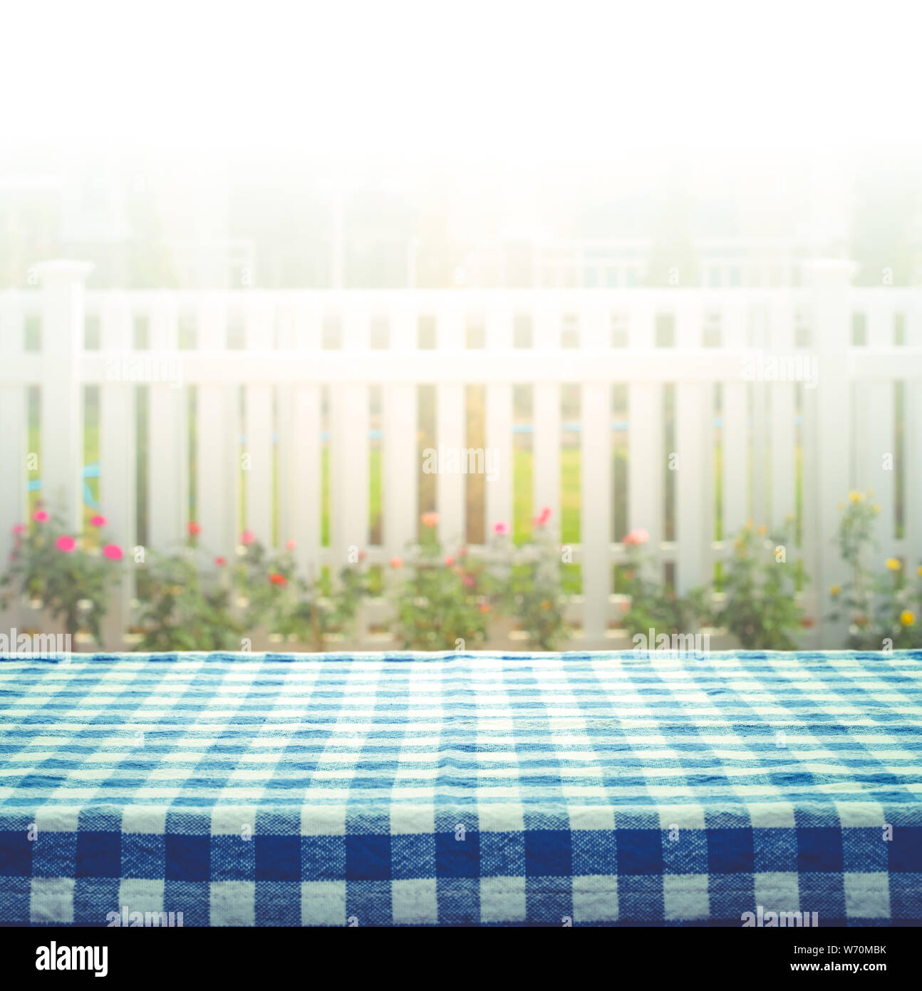 Checkered tablecloth on blur of white fence and garden background.For ...