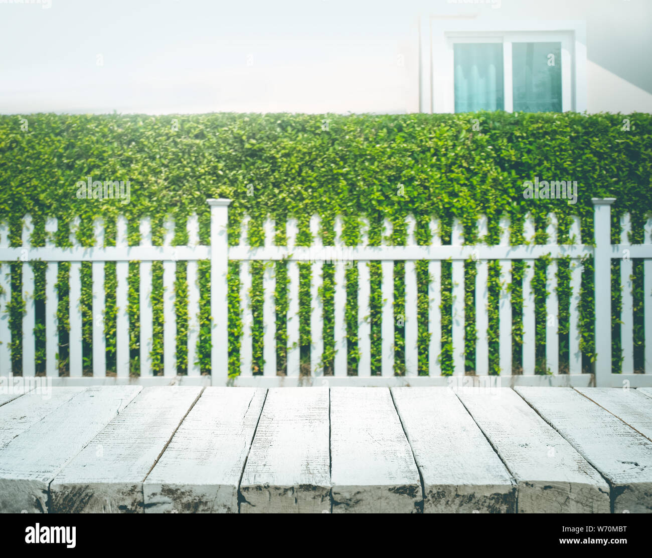 Wood table top on blur of white fence and garden background.For montage ...