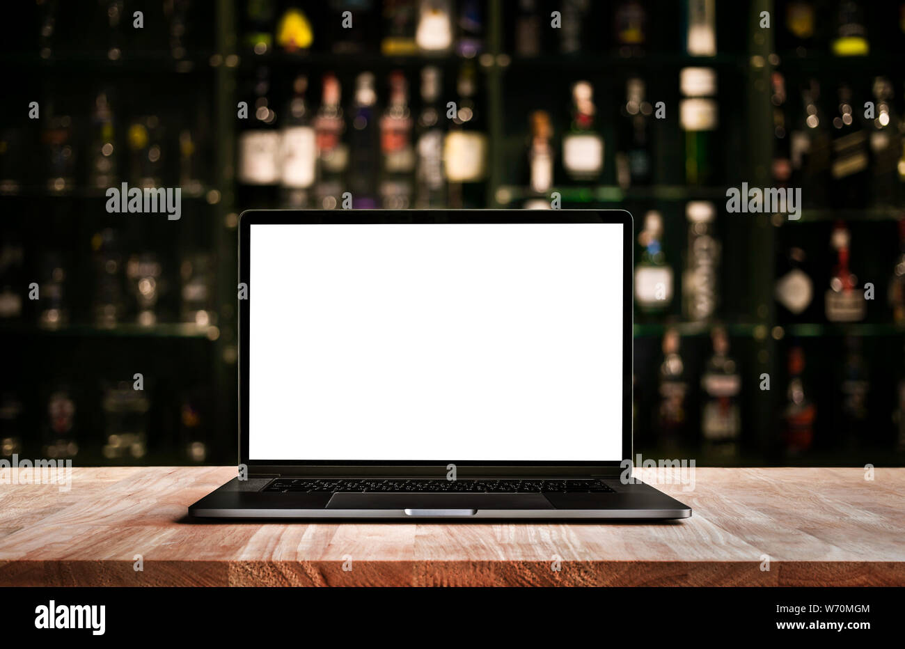 Modern computer,laptop on counter bar with blur wine bottle background ...