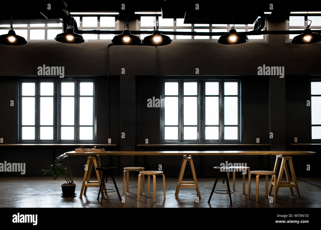 Work table in dark loft cafe design with big window Stock Photo - Alamy