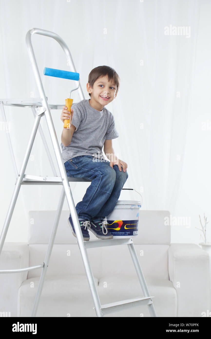 Boy sitting on a step ladder with paint roller Stock Photo - Alamy