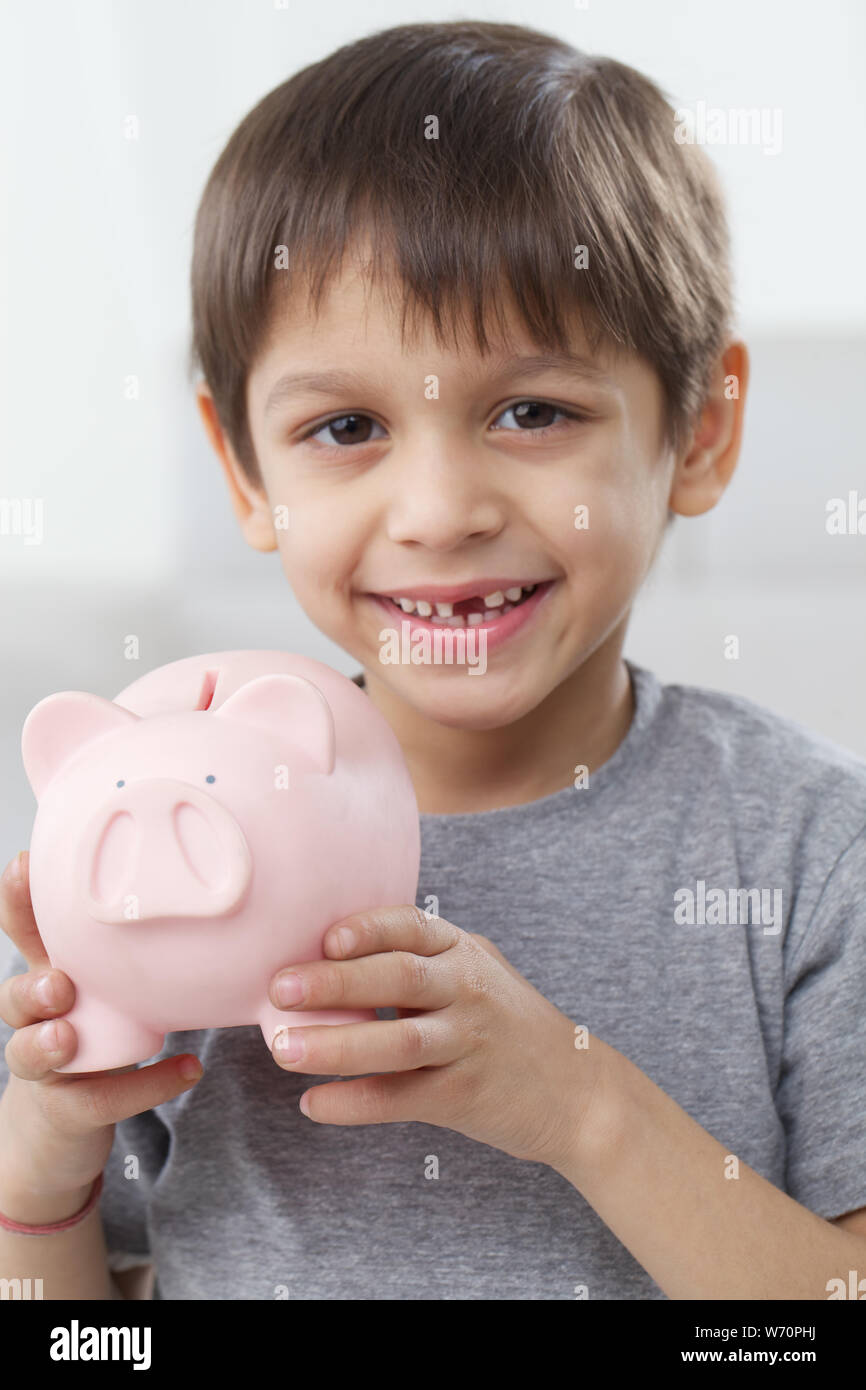 Boy holding a piggy bank and smiling Stock Photo - Alamy