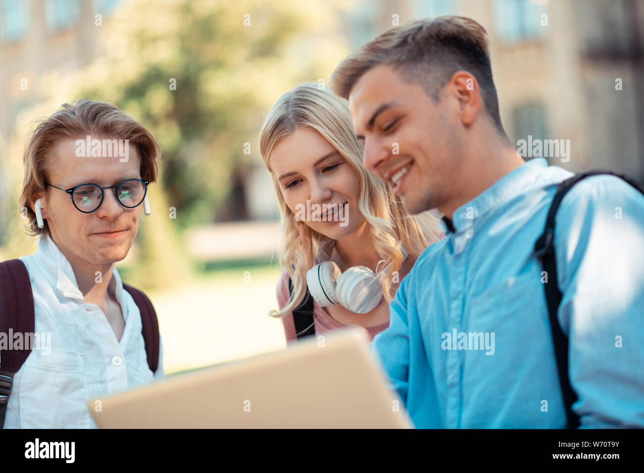 Three students looking at their project outside Stock Photo - Alamy
