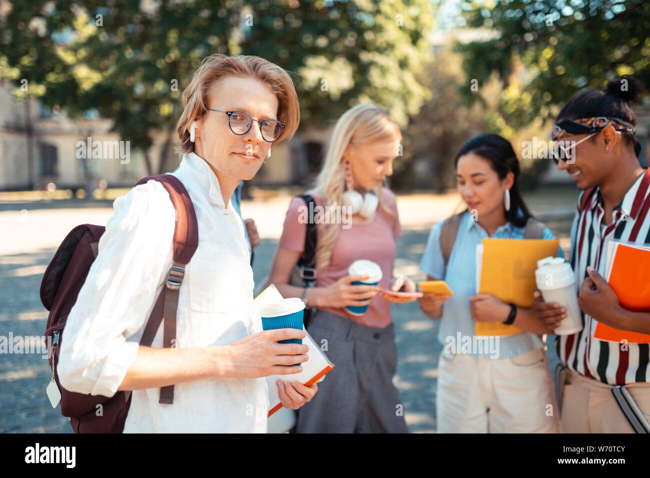 Smiling boy drinking coffee with his groupmates Stock Photo - Alamy