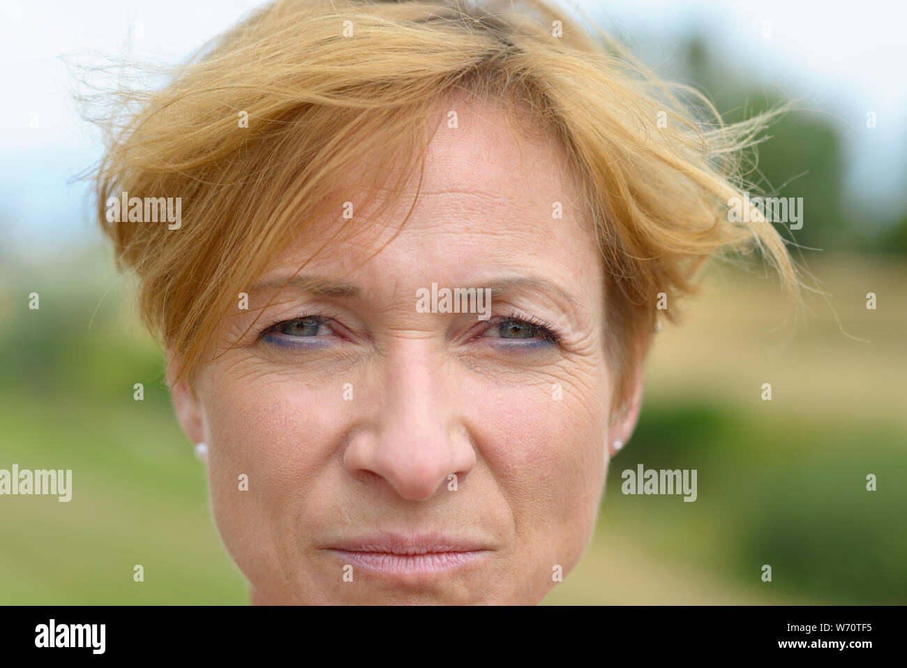 Serious woman scrutinising the camera with a quiet thoughtful stare in ...
