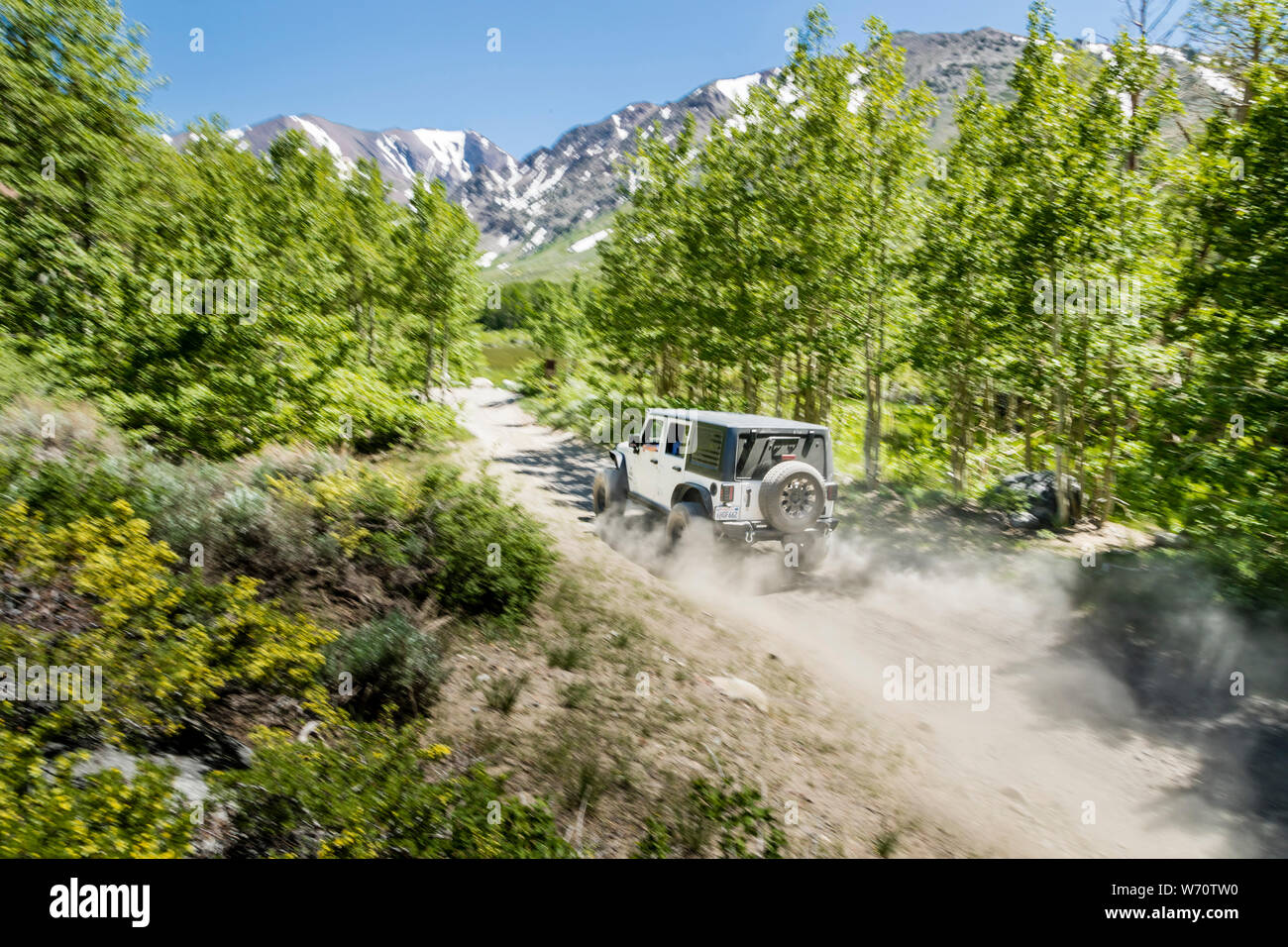 Jeep on dirt road in Sierras with mountain peaks and green valley Stock ...