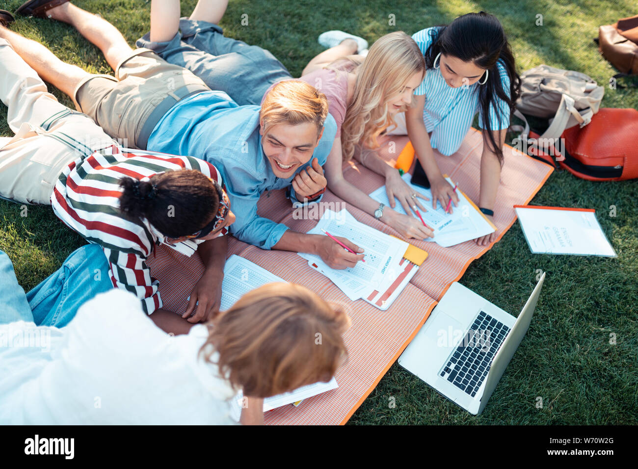 Cheerful boy doing homework among his friends Stock Photo - Alamy