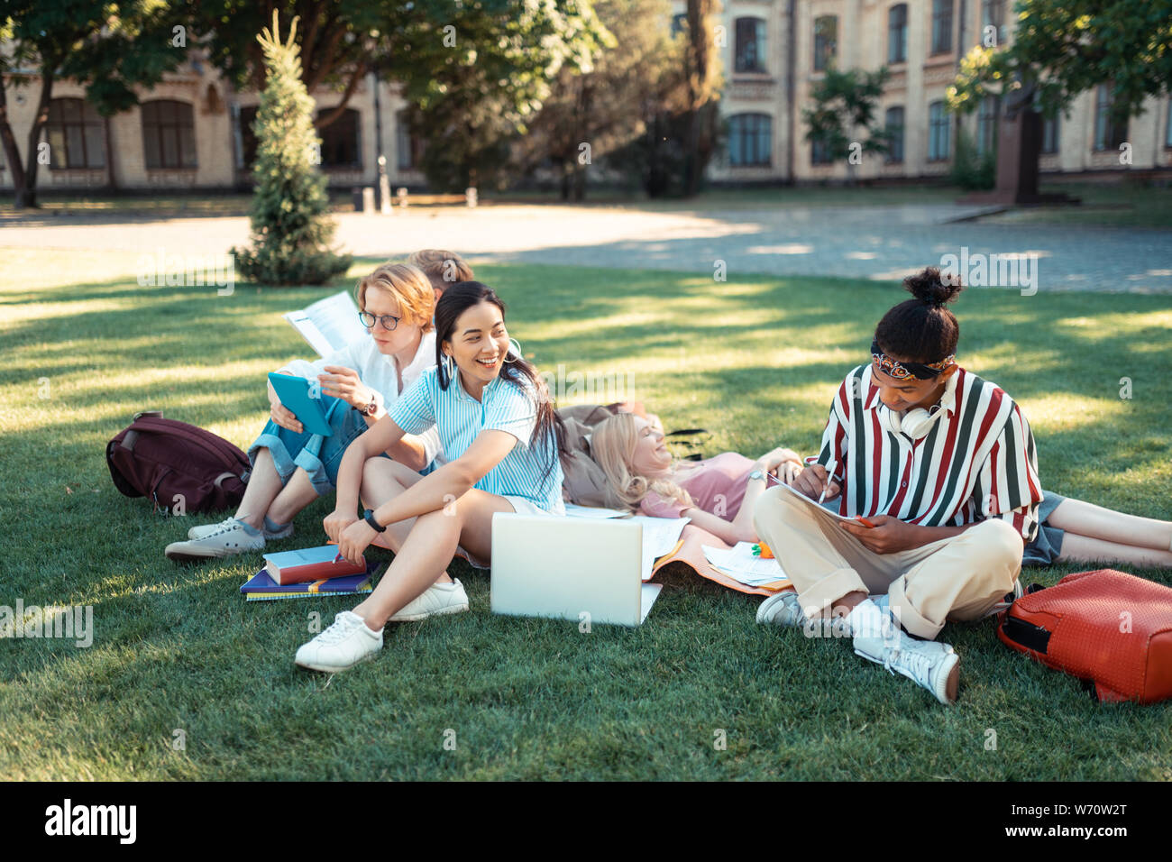 Friendly students sitting together on the grass after classes Stock ...