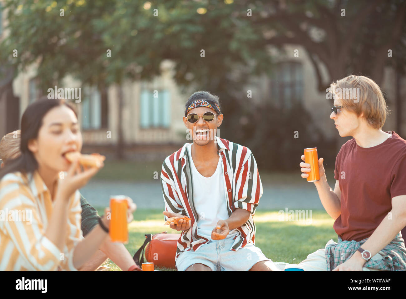 Handsome boy laughing eating with his friends Stock Photo - Alamy
