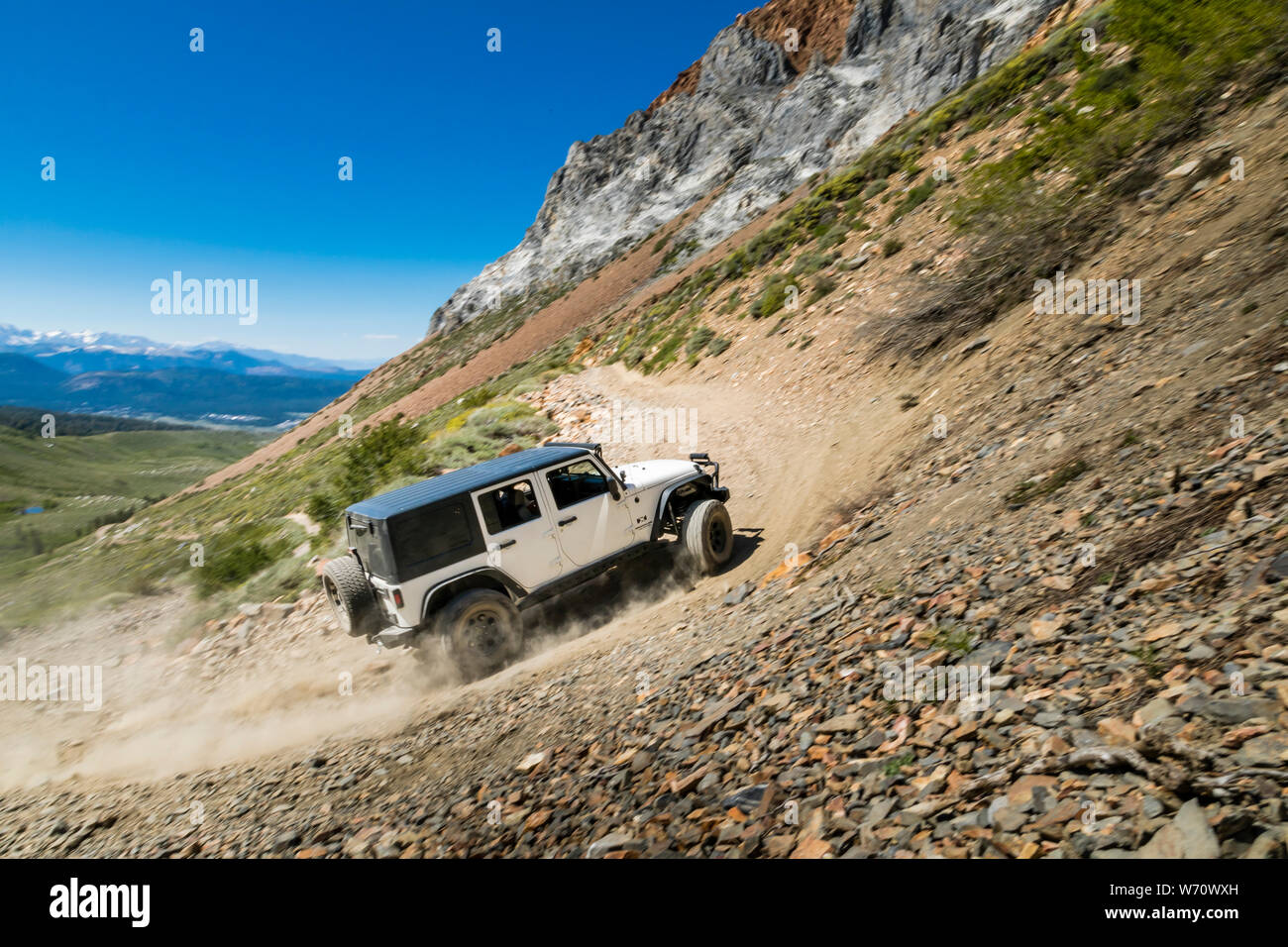 Jeep on dirt road in Sierras with mountain peaks and green valley Stock ...
