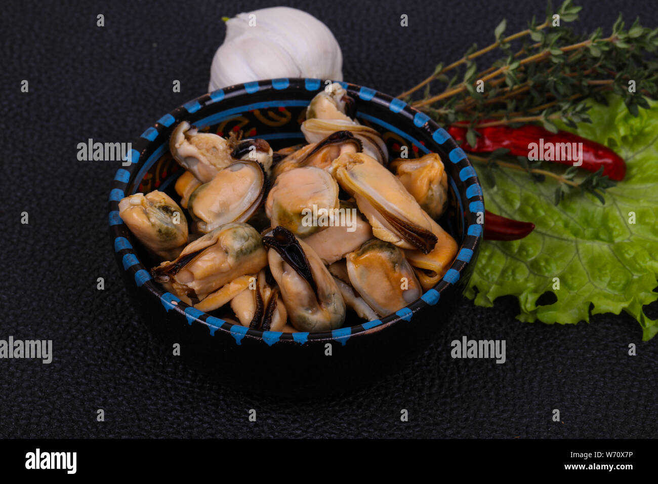 Pickled mussels in the bowl served pepper, garlic and salad leaves ...