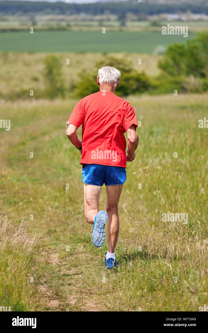 Senior runner running on the meadow road Stock Photo - Alamy